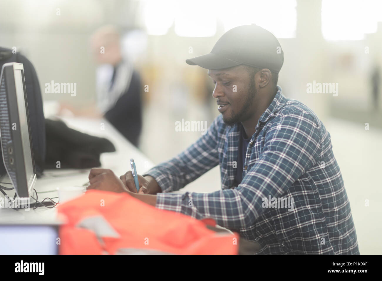 Man sitting at desk working with a safety vest next to him Stock Photo ...