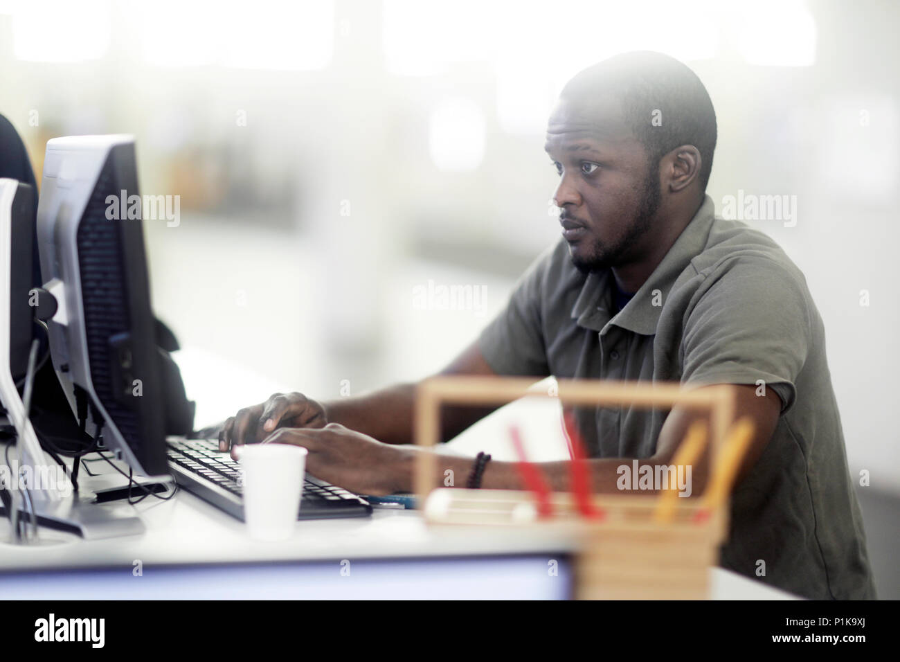 Man sitting at desk using a computer with tools on his desk Stock Photo ...