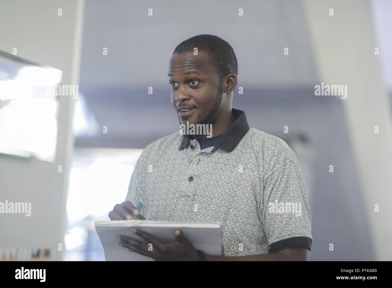 Man standing in office writing on a notepad Stock Photo - Alamy