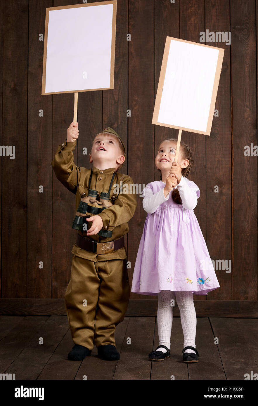 Children boy are dressed as soldier in retro military uniforms and girl ...