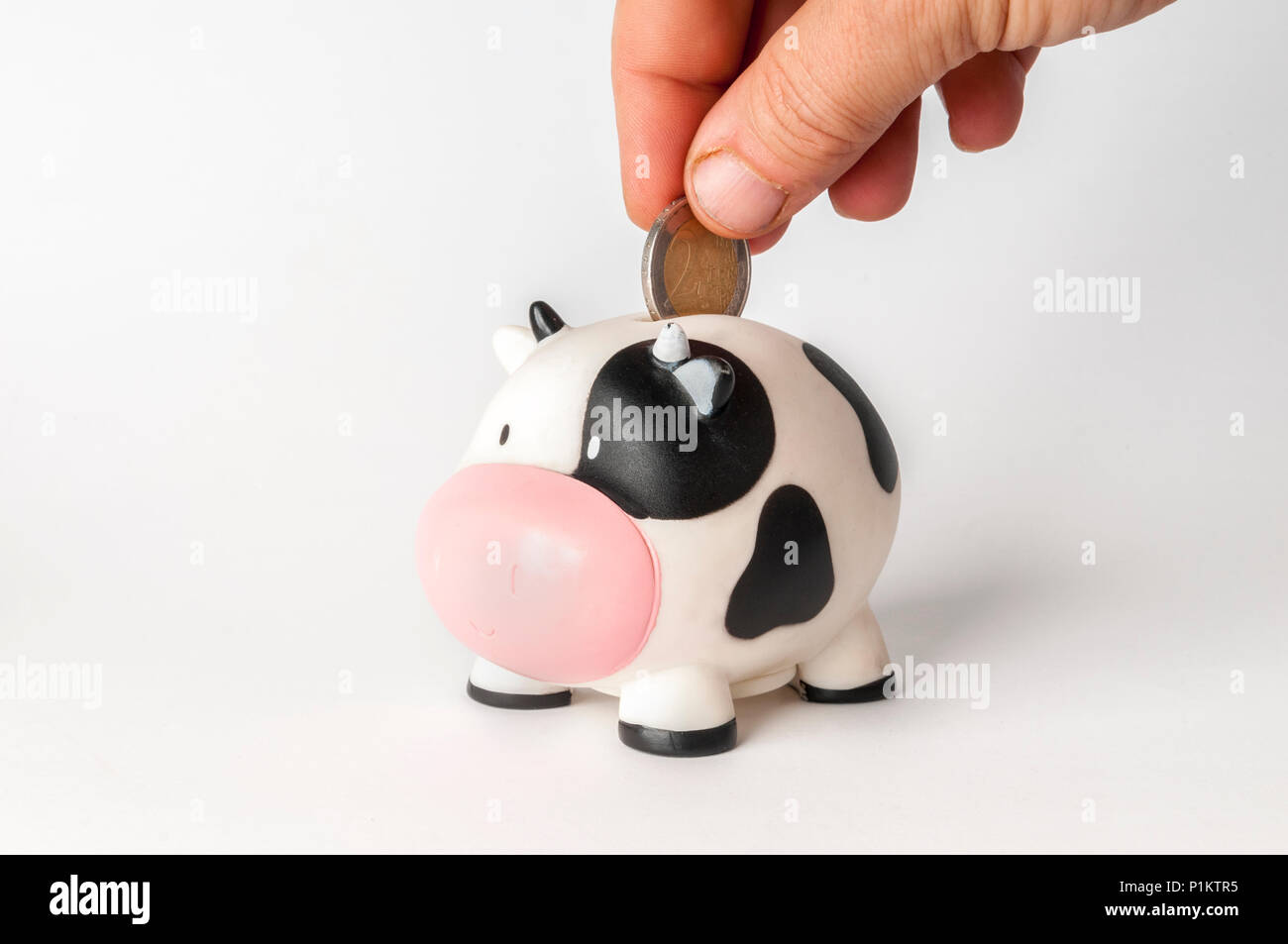 Hand put a 2 euro coin into a money box Stock Photo - Alamy