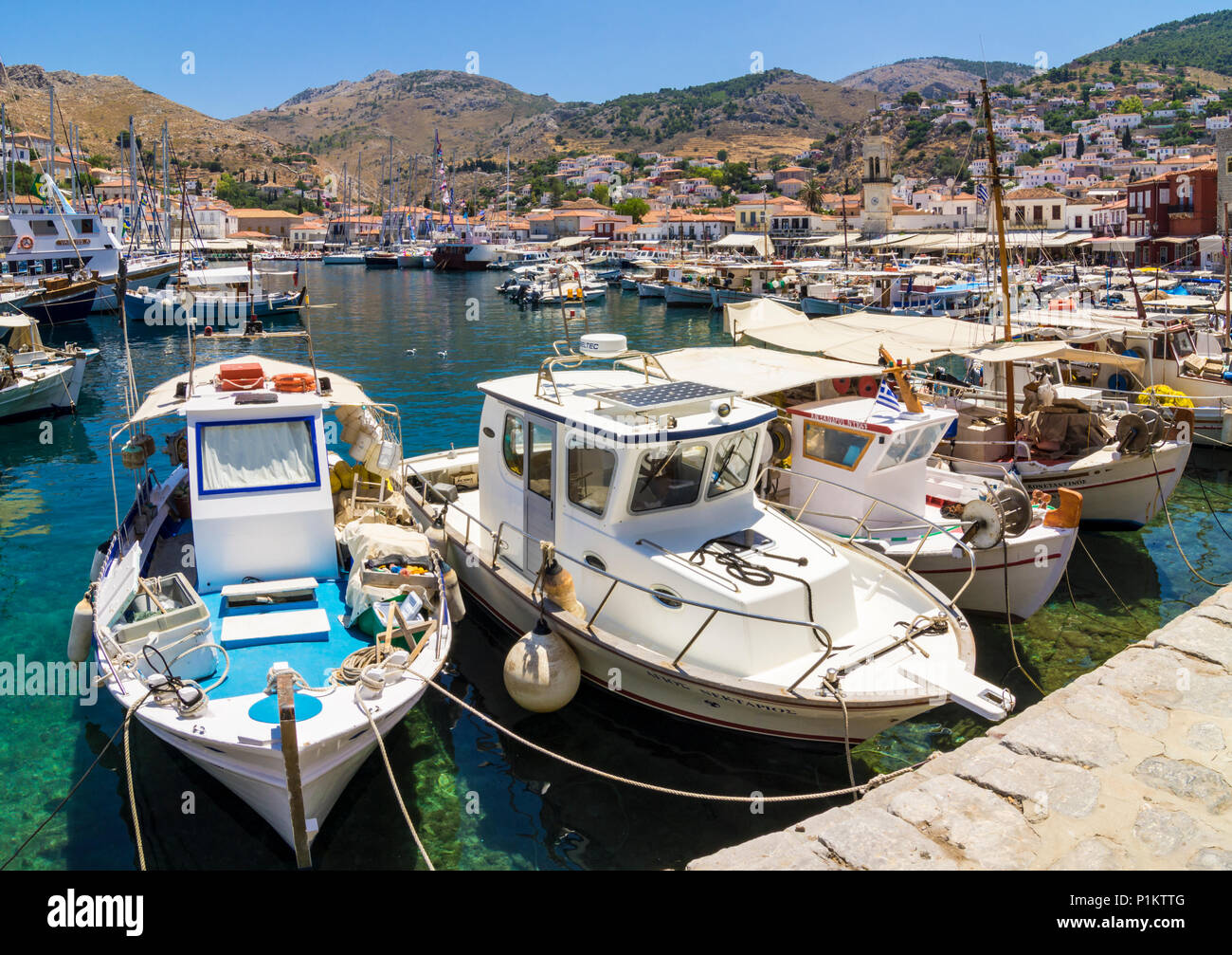 Hydra Town harbour filled with small fishing boats overlooked by the ...