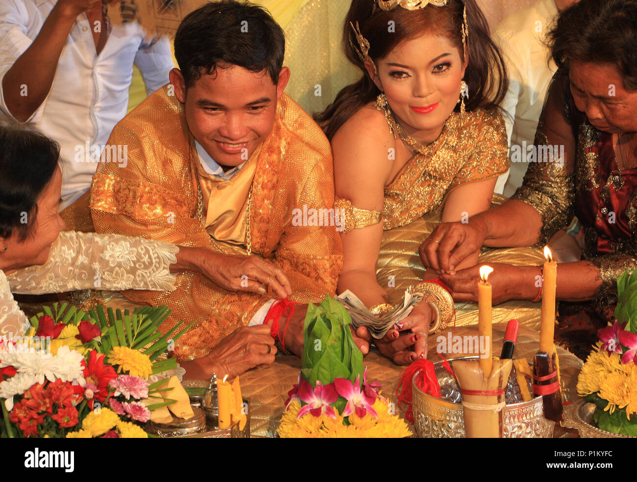 The wedding guests tie red cotton on the wrists of the bride and groom ...