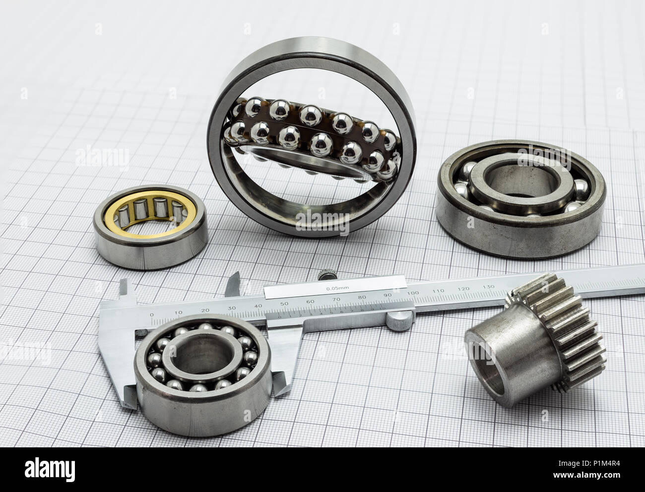 Vernier caliper lying on drafting paper with bearings and small gear ...