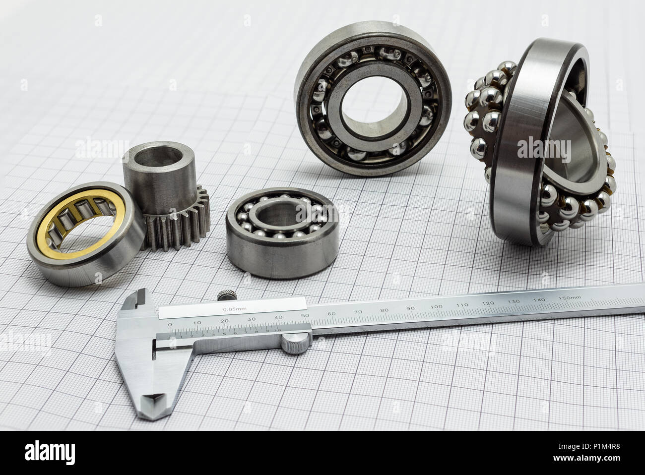 Vernier caliper lying on drafting paper with bearings and small gear ...