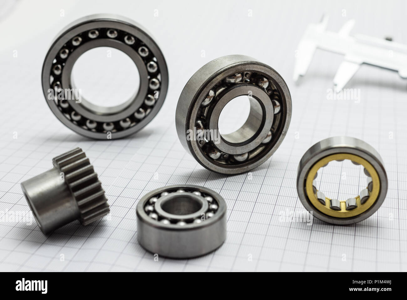 Vernier caliper lying on drafting paper with bearings and small gear ...
