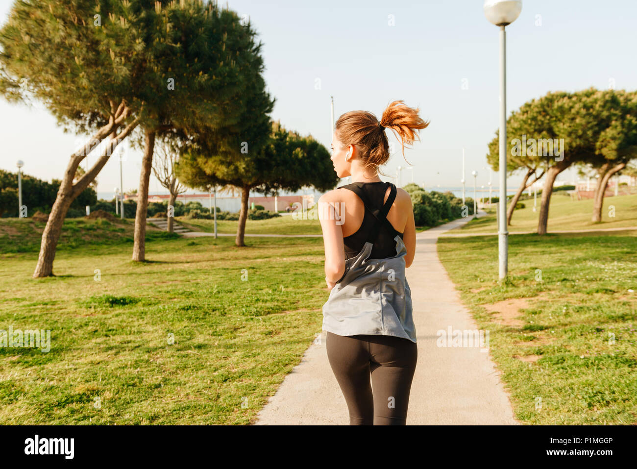 Back view photo of attractive young sports woman running outdoors in ...