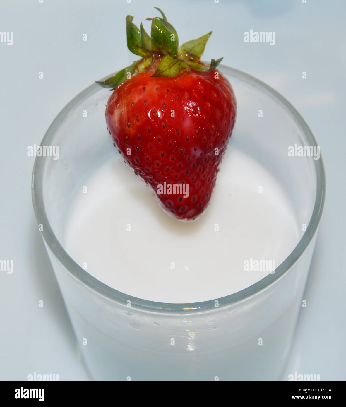 strawberry drop on milk glass Stock Photo - Alamy