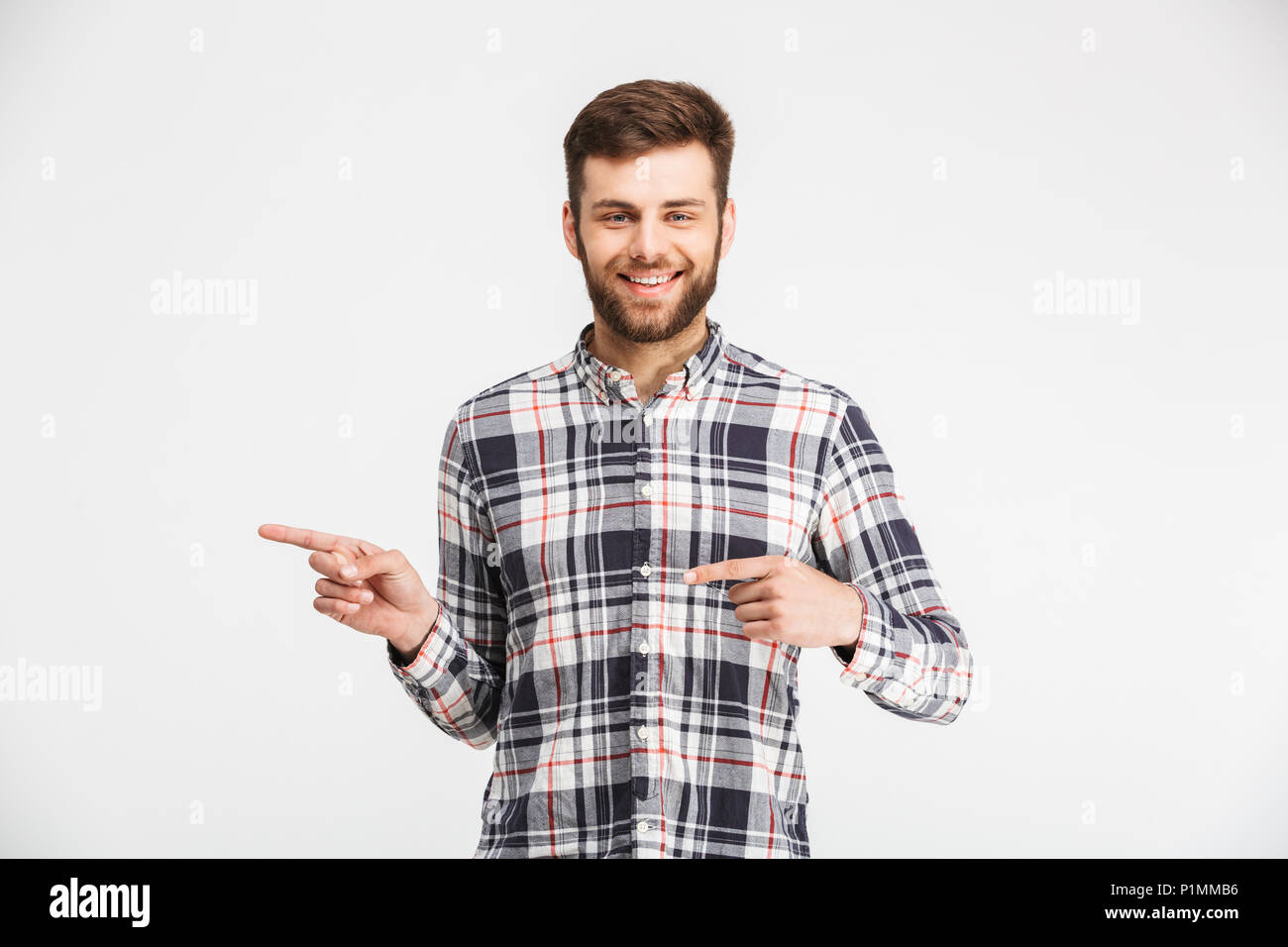 Portrait of a cheerful man pointing fingers away at copy space isolated ...