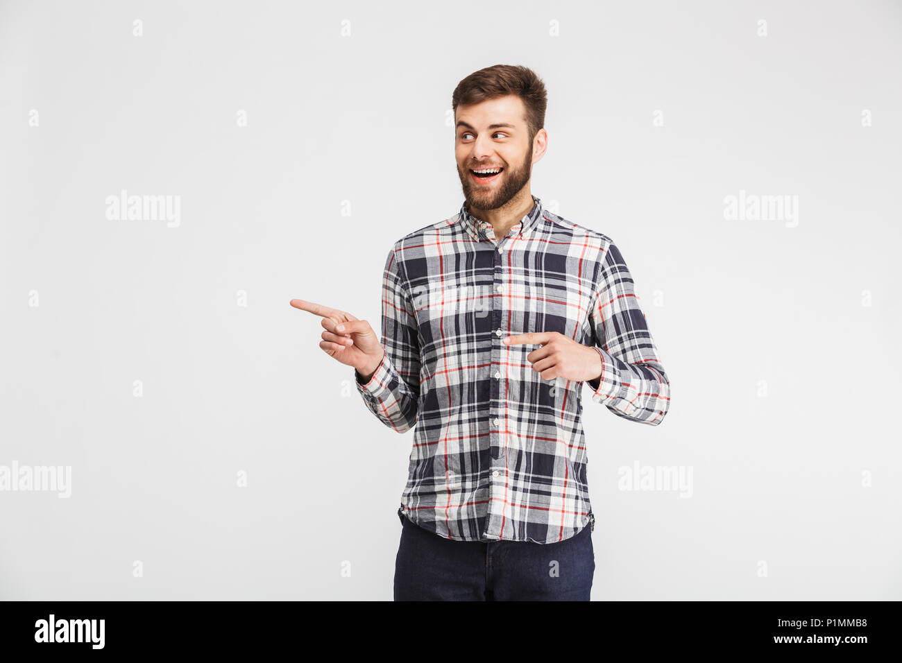 Portrait of a happy man pointing fingers away at copy space isolated ...