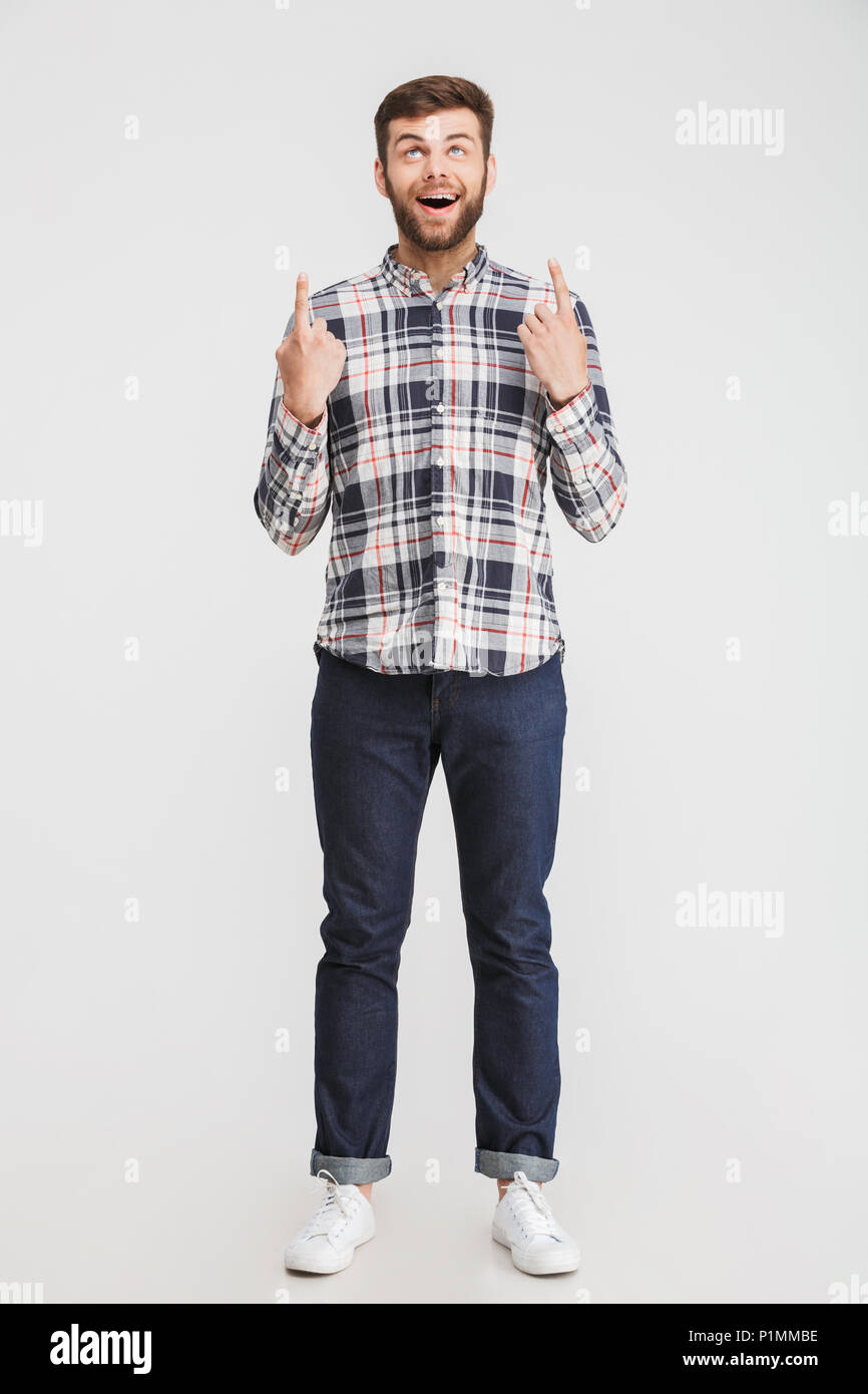 Full length portrait of an excited man pointing fingers up at copy ...