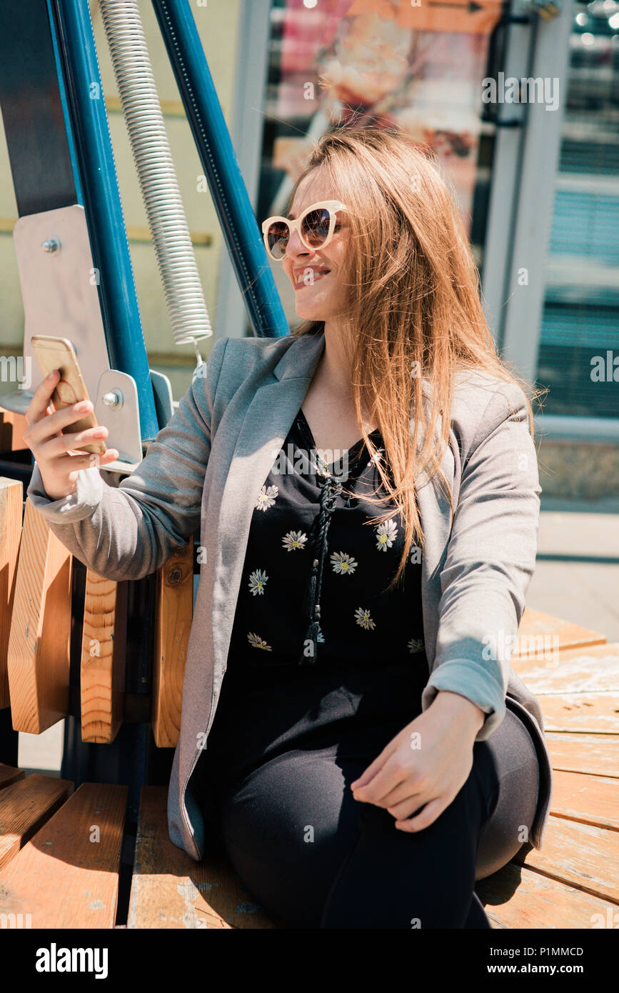 Happy casual woman calling on the phone sitting on a bench in the ...