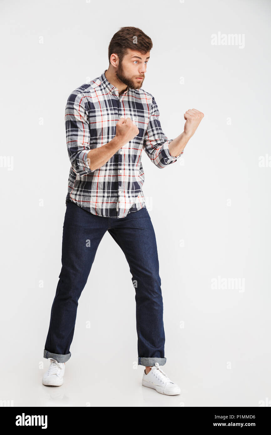 Full length portrait of an angry young man standing in a fighting ...