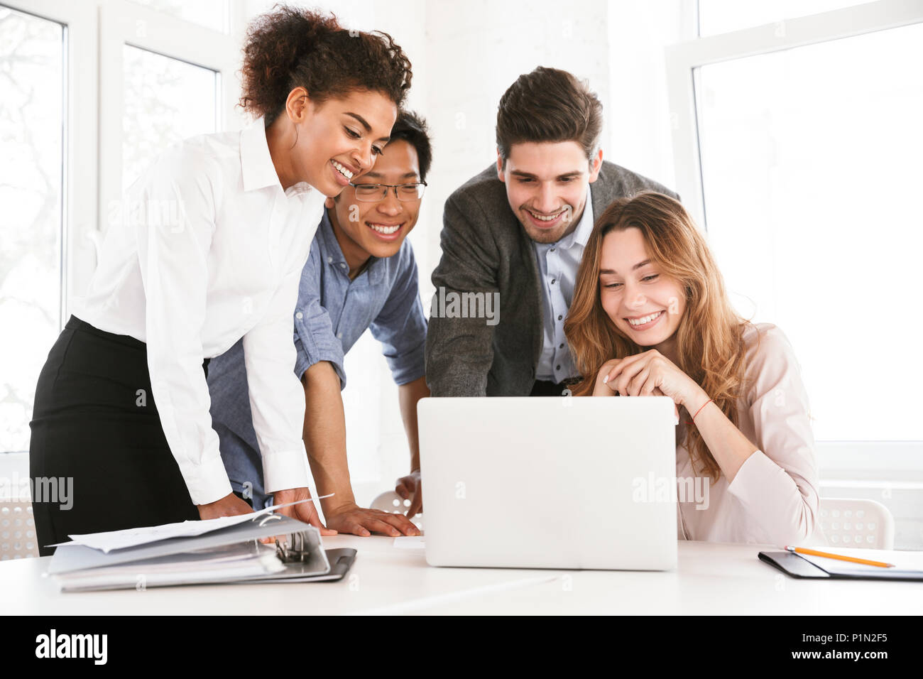 Group of cheerful young multiethnic businesspeople discussing ideas ...