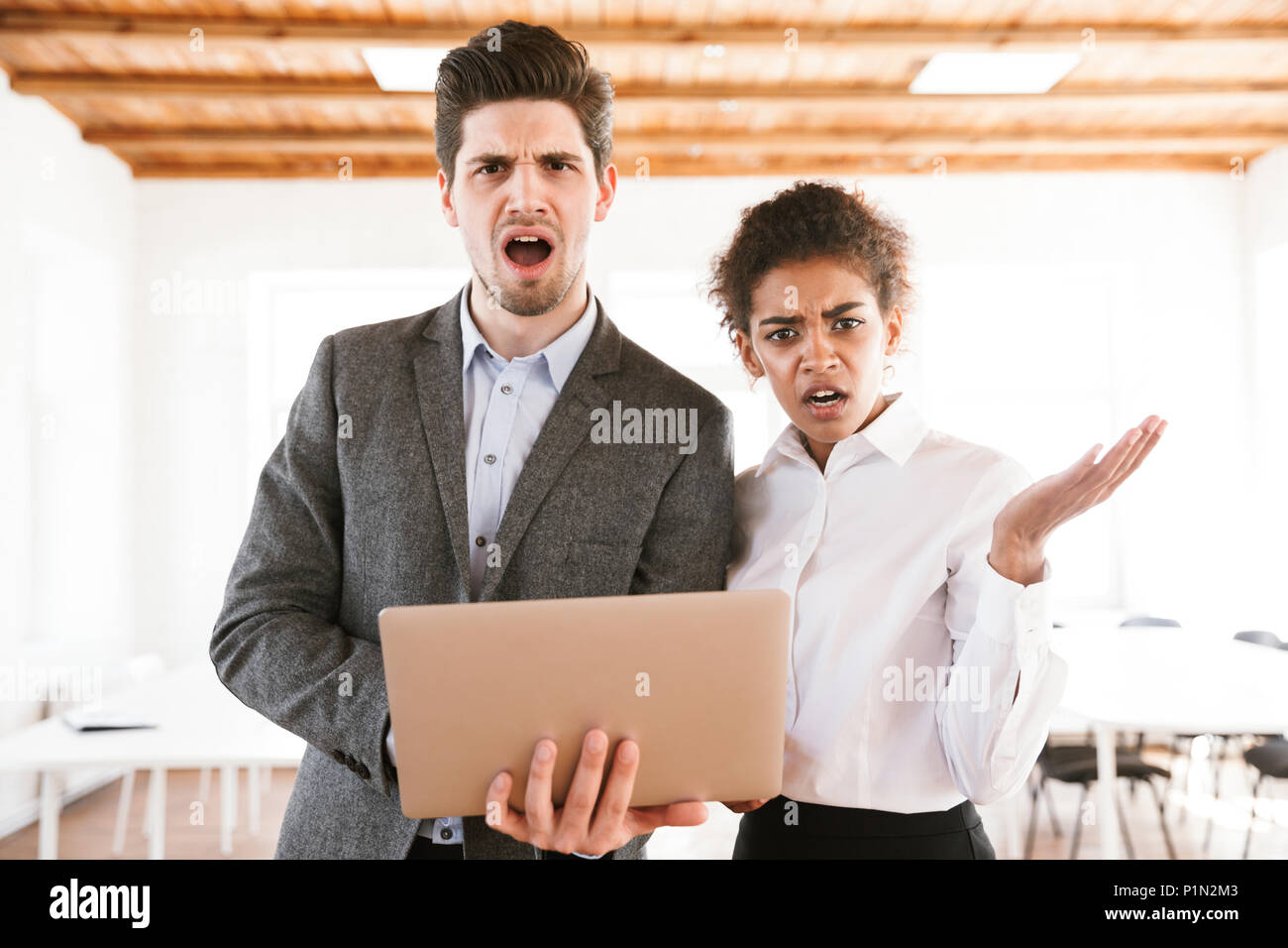 Confused multhiethnic business couple working on laptop computer while ...
