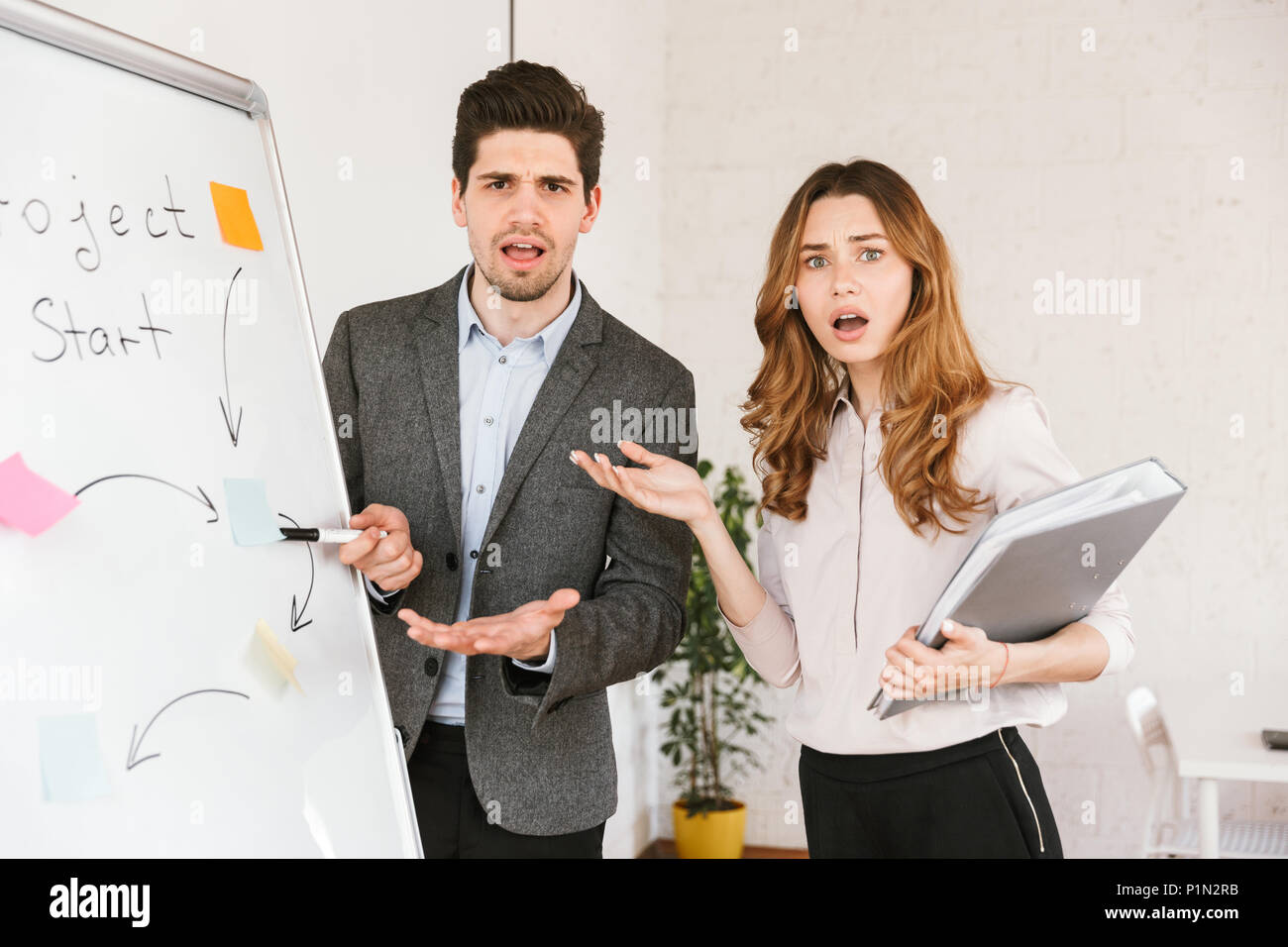 Confused young business couple presenting a project at the office Stock ...