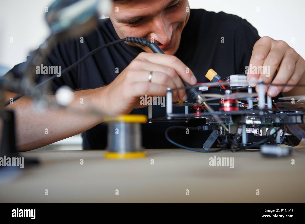 Image of man with soldering iron repairing mechanism in room Stock ...