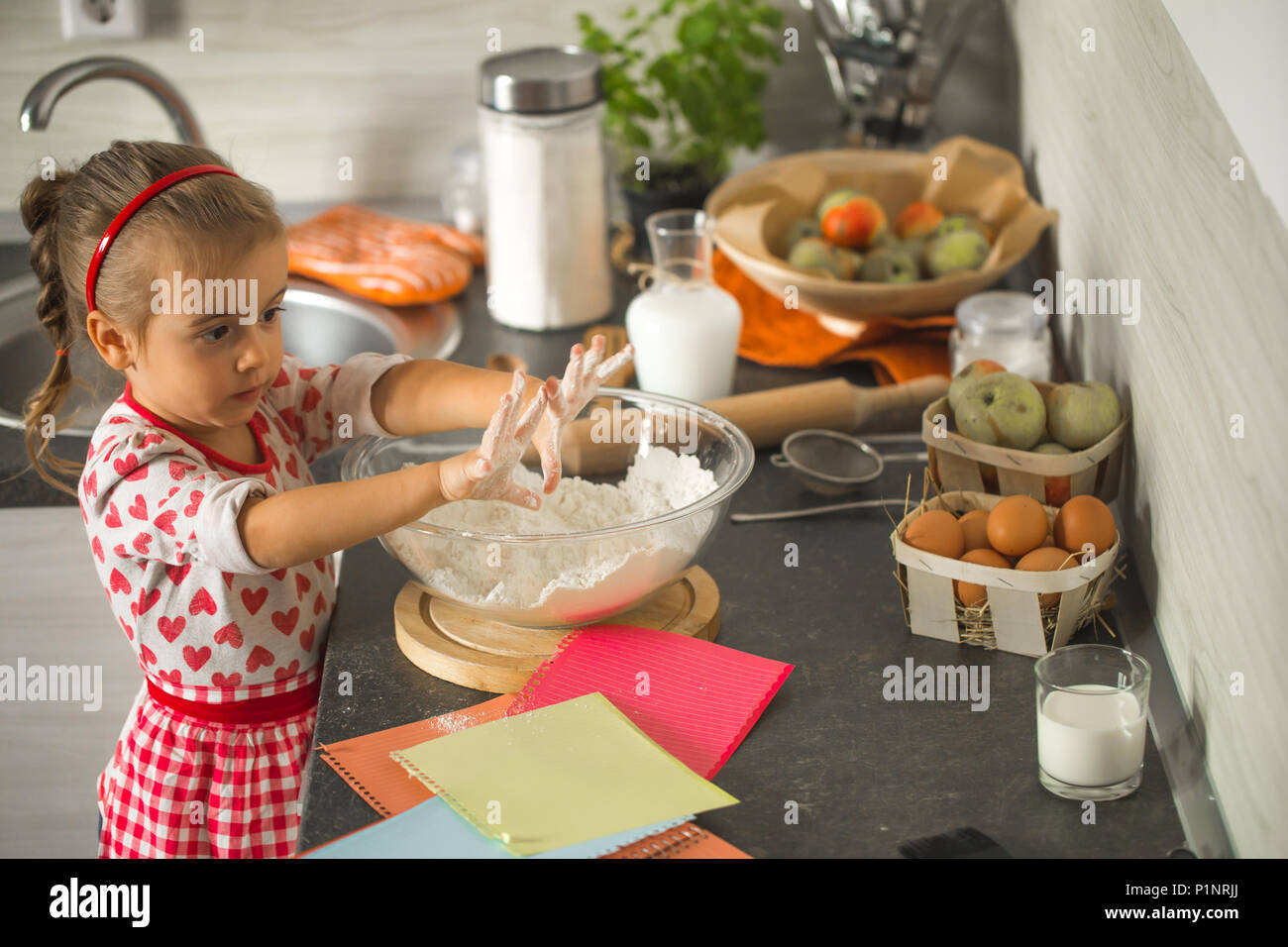 beautiful little girl Baker on kitchen with ingredients for baking ...