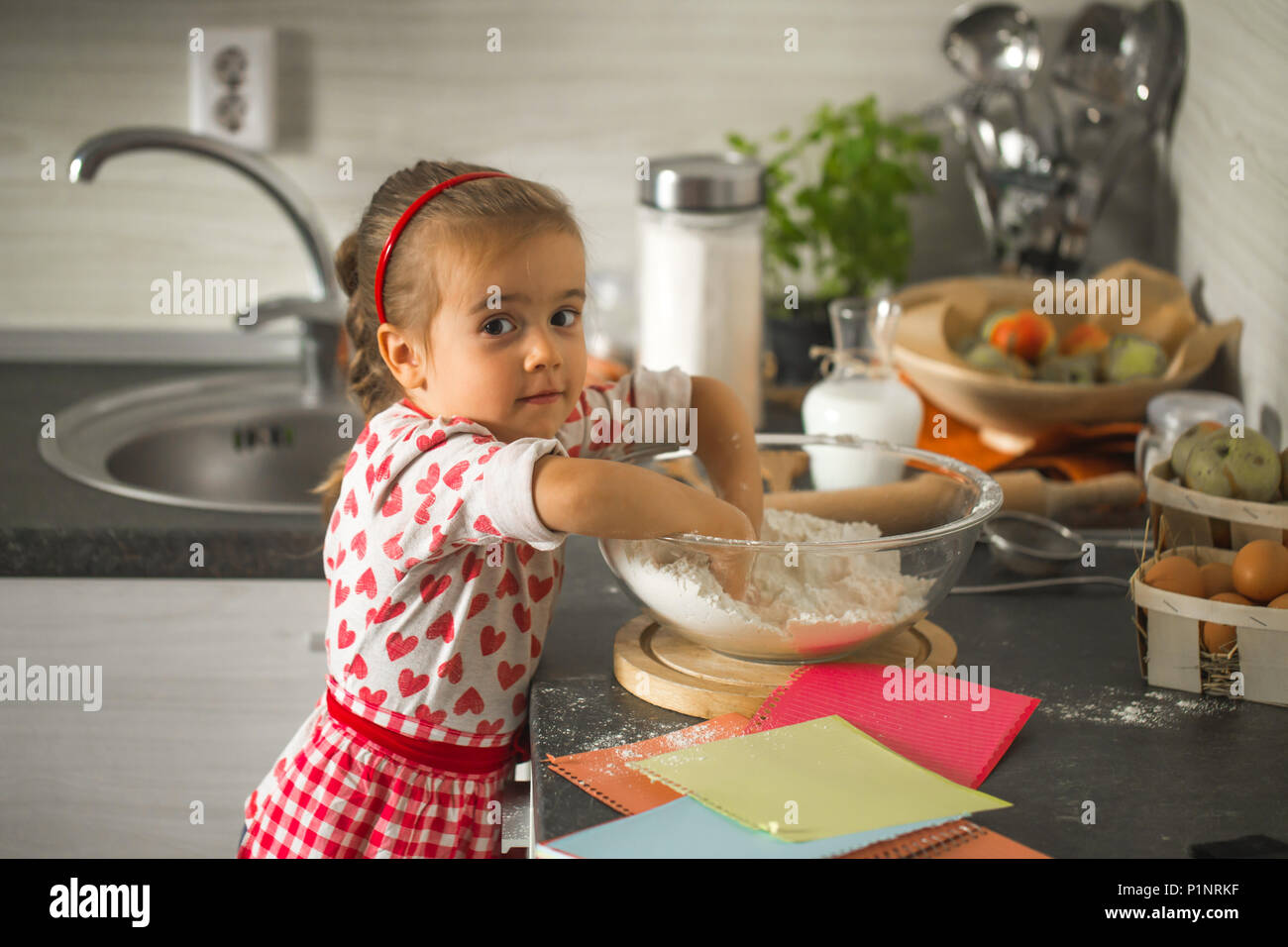 beautiful little girl Baker on kitchen with ingredients for baking ...