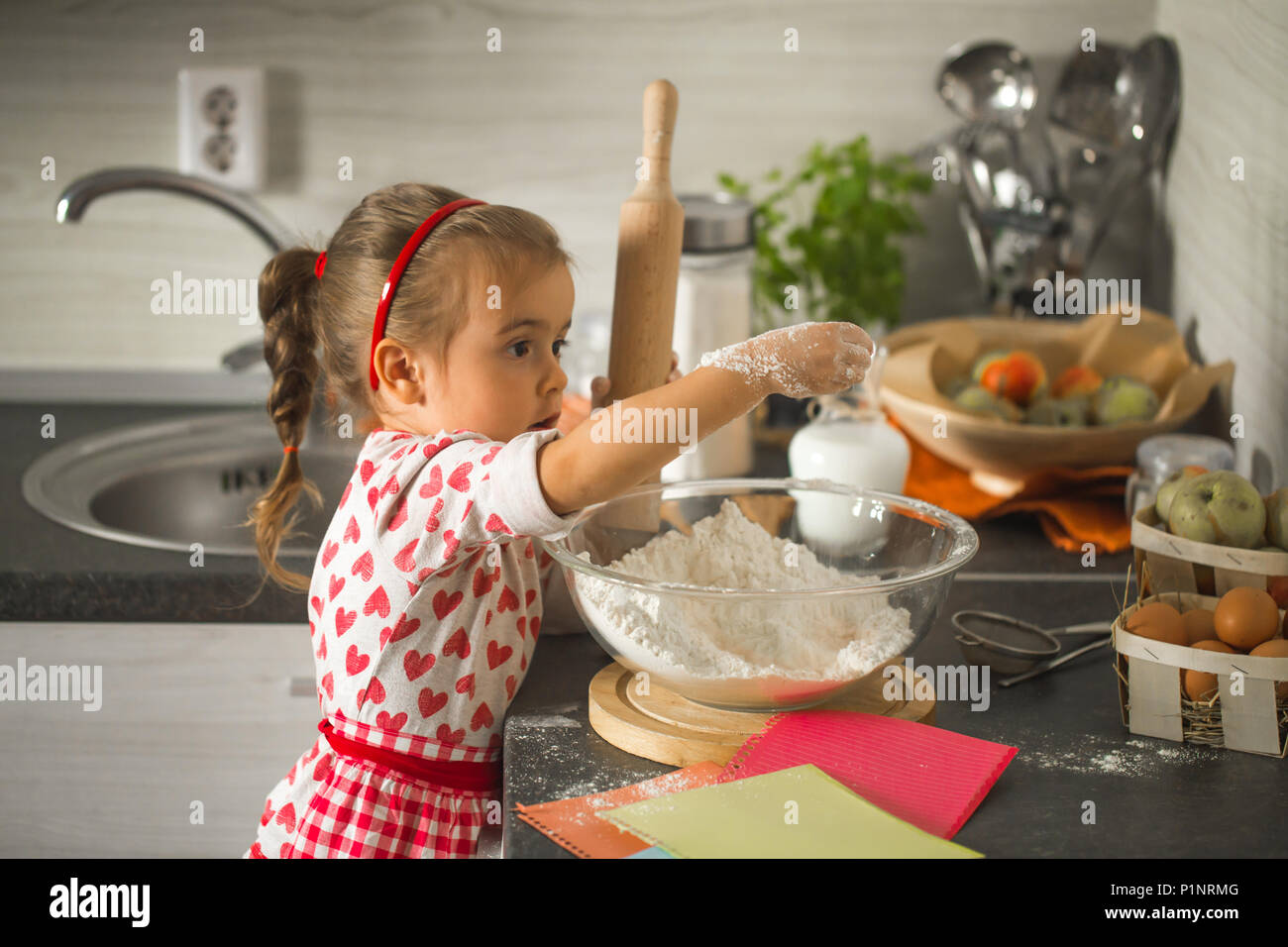 beautiful little girl Baker on kitchen with ingredients for baking ...