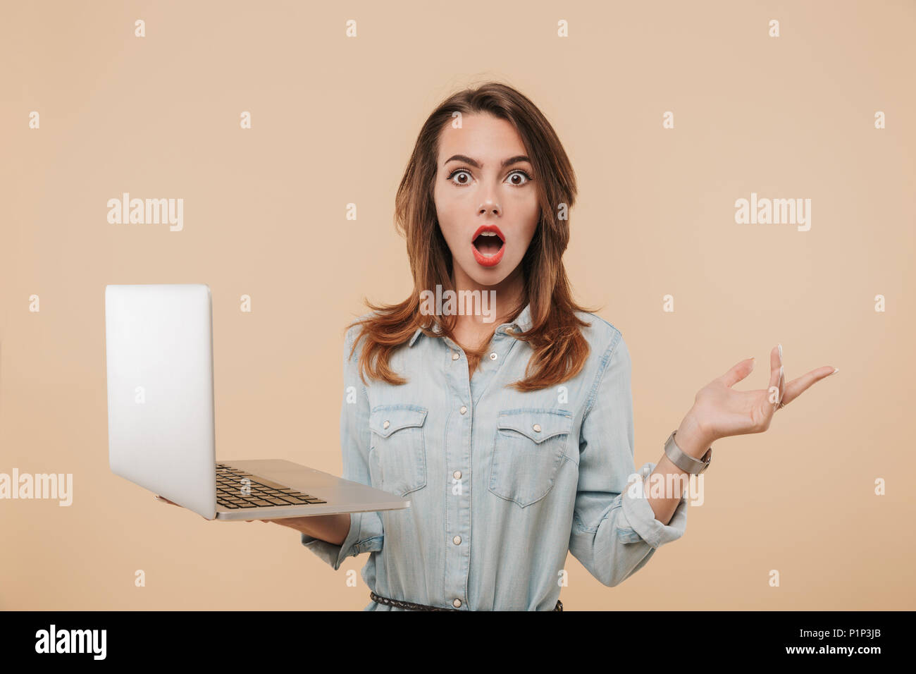 Portrait of a surprised young girl in summer clothes holding laptop ...
