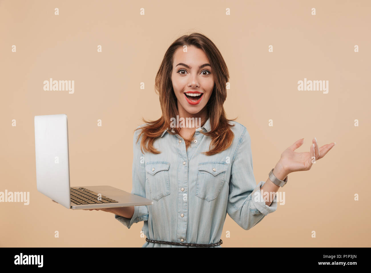 Portrait of an excited young girl in summer clothes holding laptop ...
