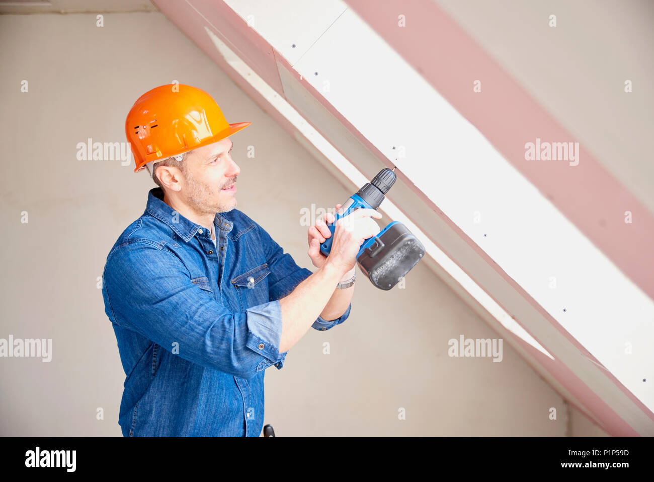 Portrait of repairman wearing safety helmet while working with cordless ...