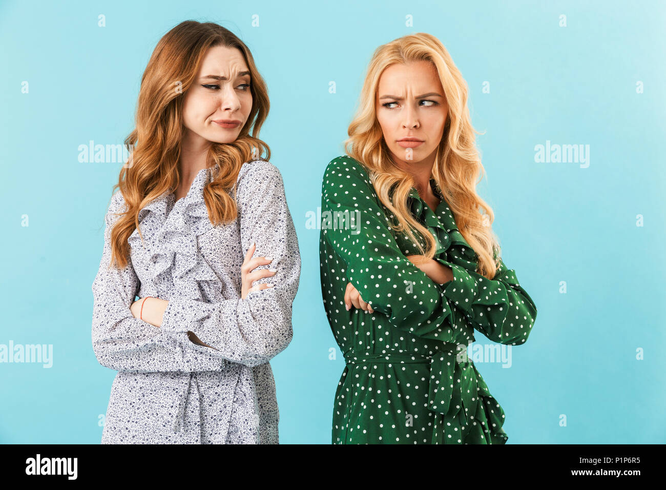 Two offended women in dresses standing back to each other with crossed ...