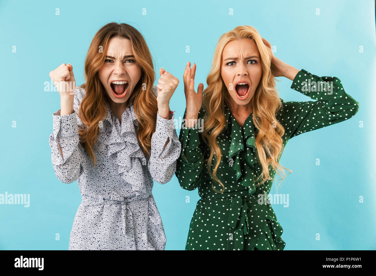 Two confused women in dresses screaming and looking at the camera over ...