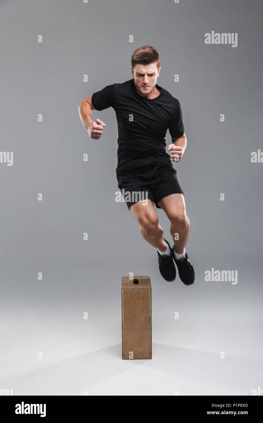 Full length portrait of a motivated young sportsman jumping over a ...