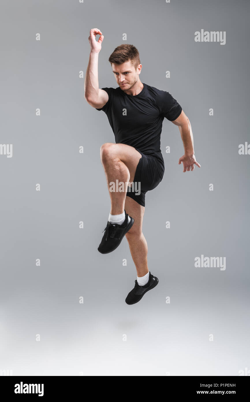 Full length portrait of a strong young sportsman jumping isolated over ...