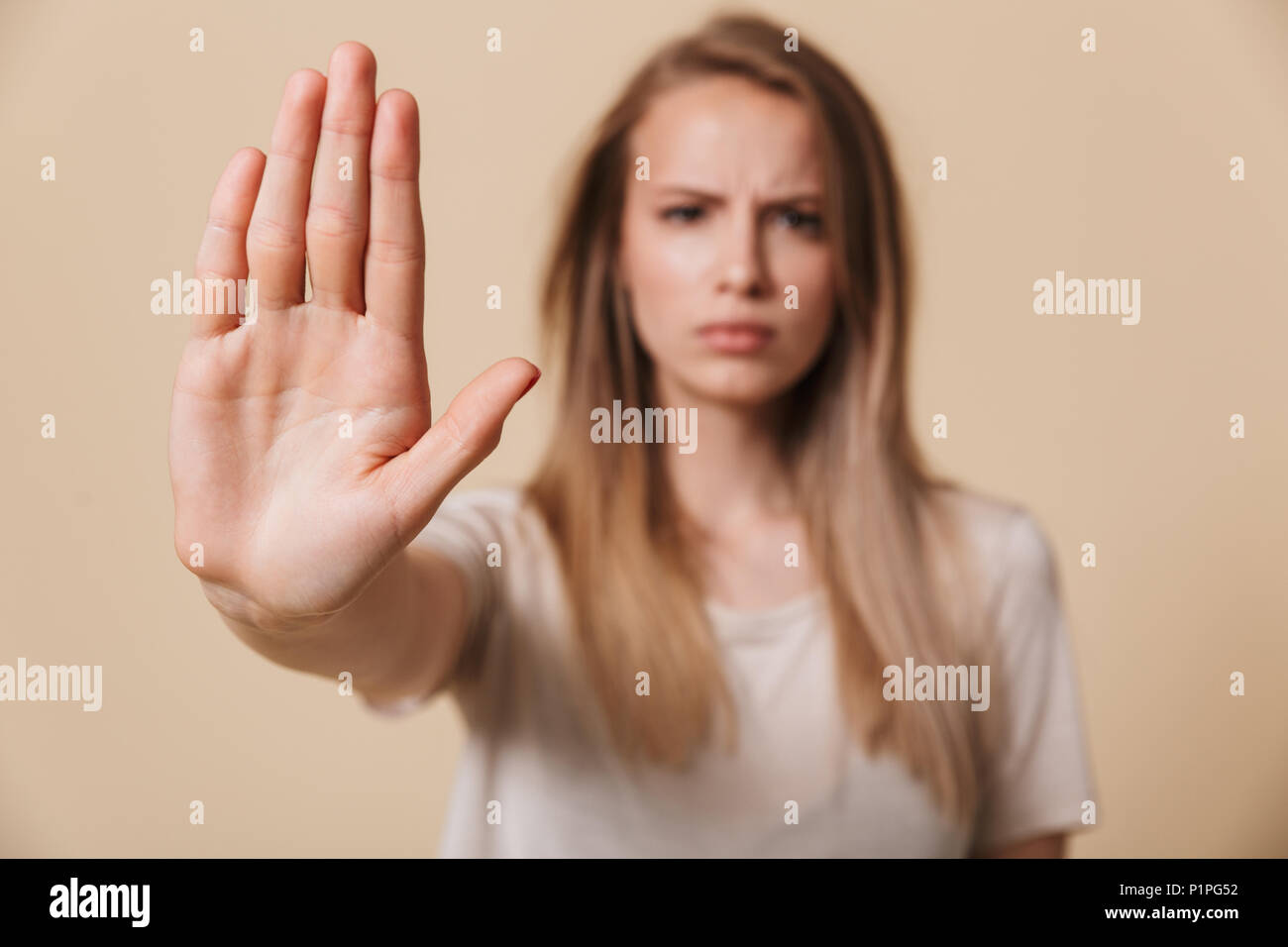 Portrait of a serious young woman showing stop gesture with her palm ...