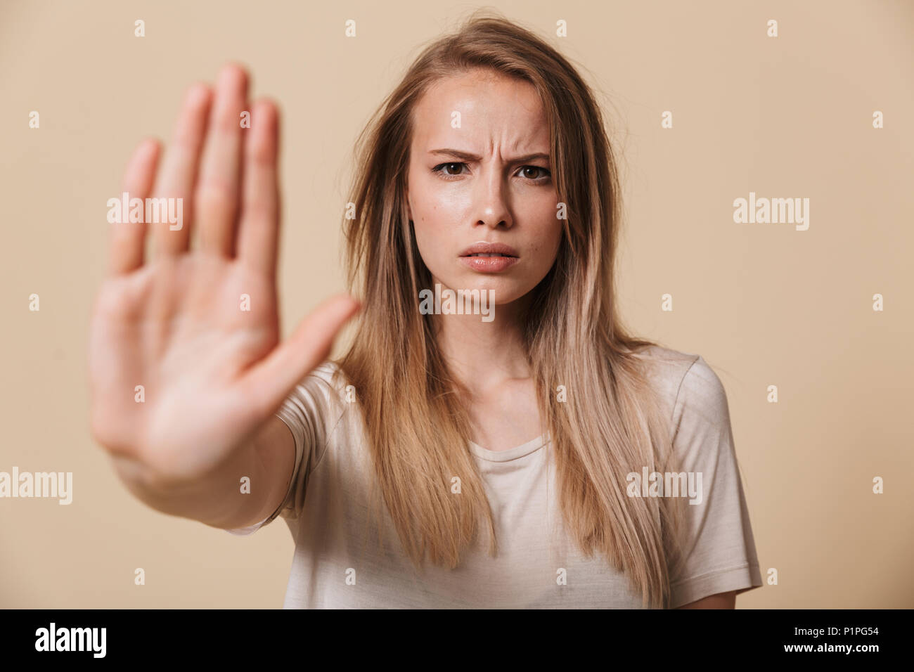 Portrait of a concentrated young woman showing stop gesture with her ...
