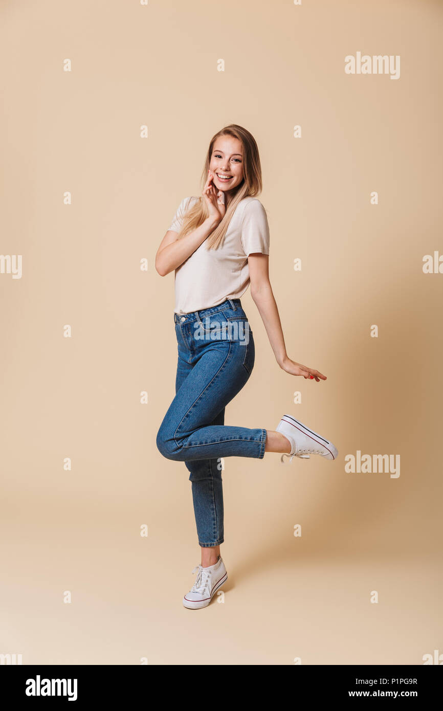 Full length portrait of a cheerful casual girl posing while standing ...