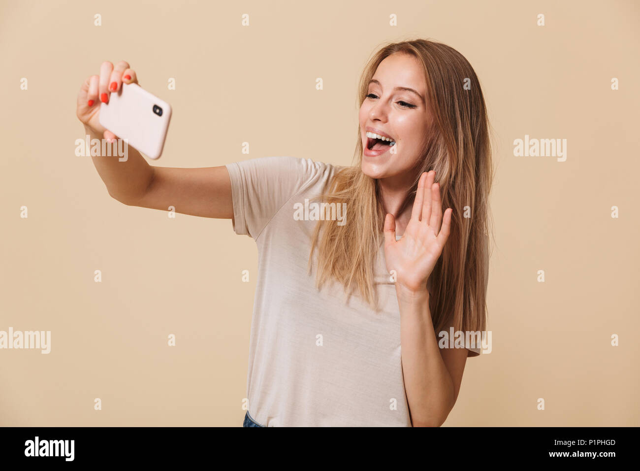Portrait of a pretty young girl taking a selfie and waving hand ...