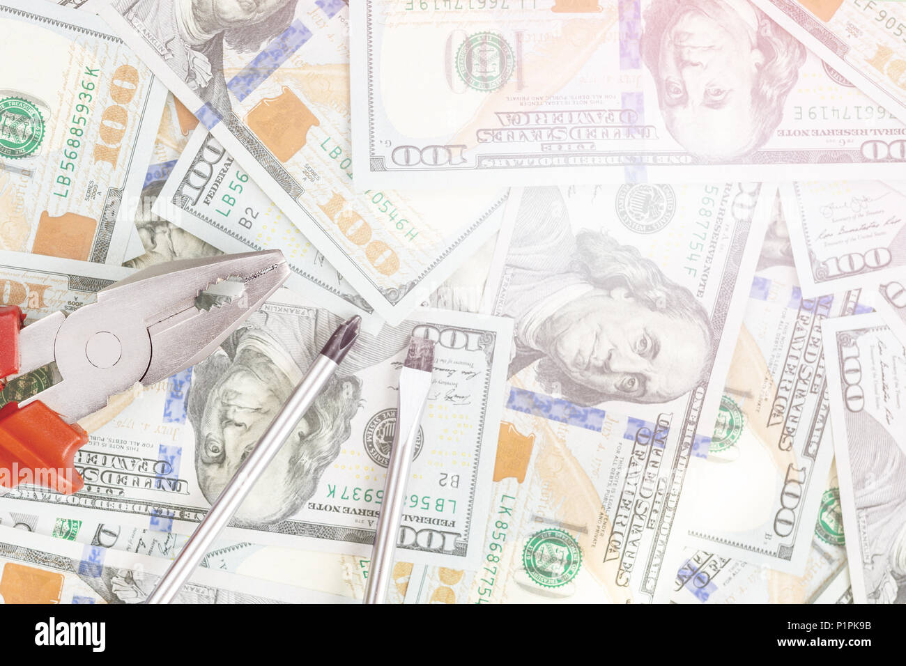 Tools lying over 100 dollars banknotes background. Pliers and ...