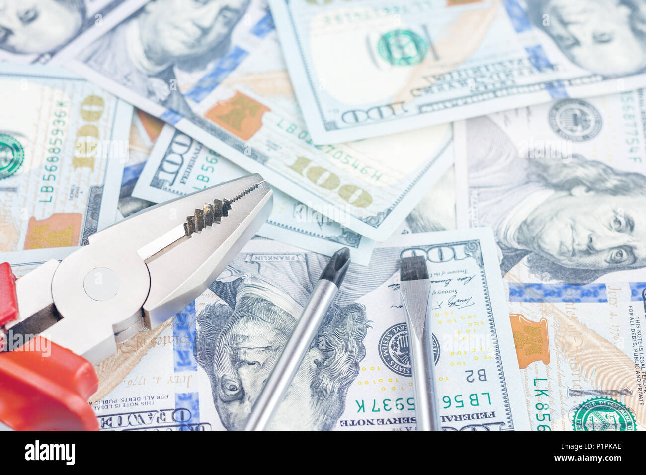 Tools lying over 100 dollars banknotes background. Pliers and ...