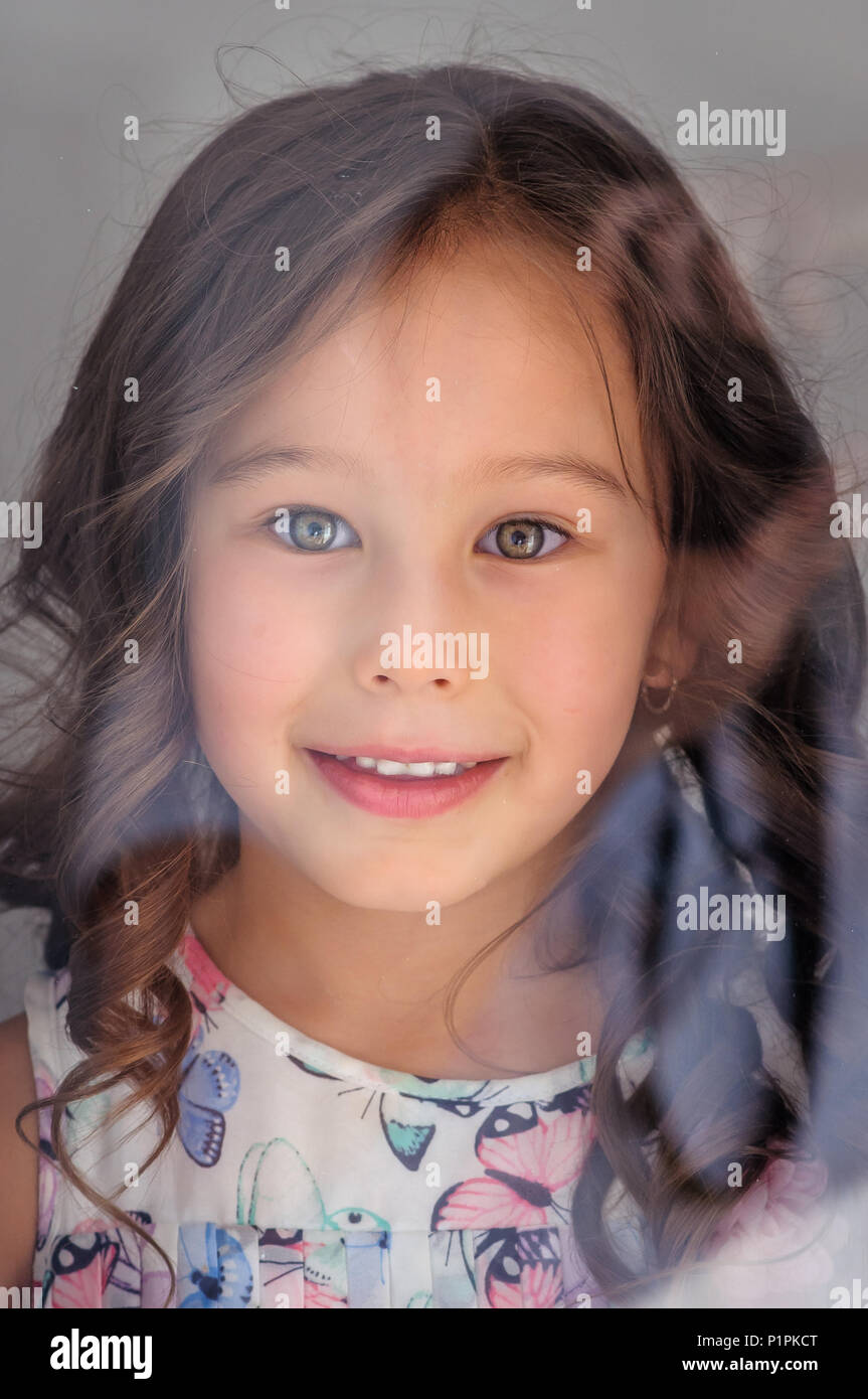 Portrait of a cute caucasian five years old girl smiling behind a ...
