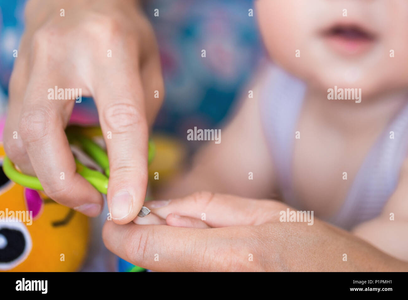 Close-up mother cutting nail of baby with safety scissors. Mom trimming ...