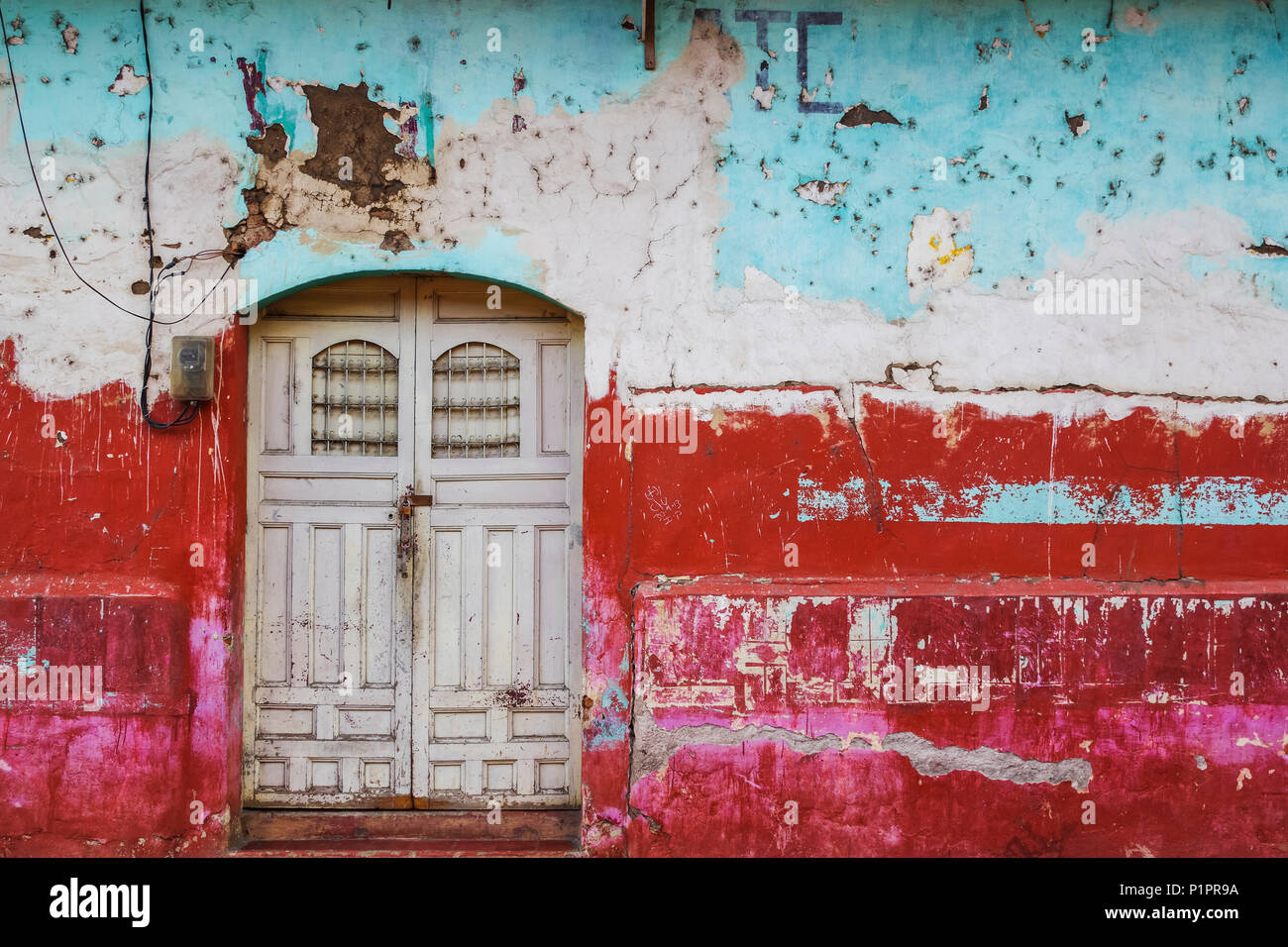 Worn and weathered facade of a building with peeling paint and double ...