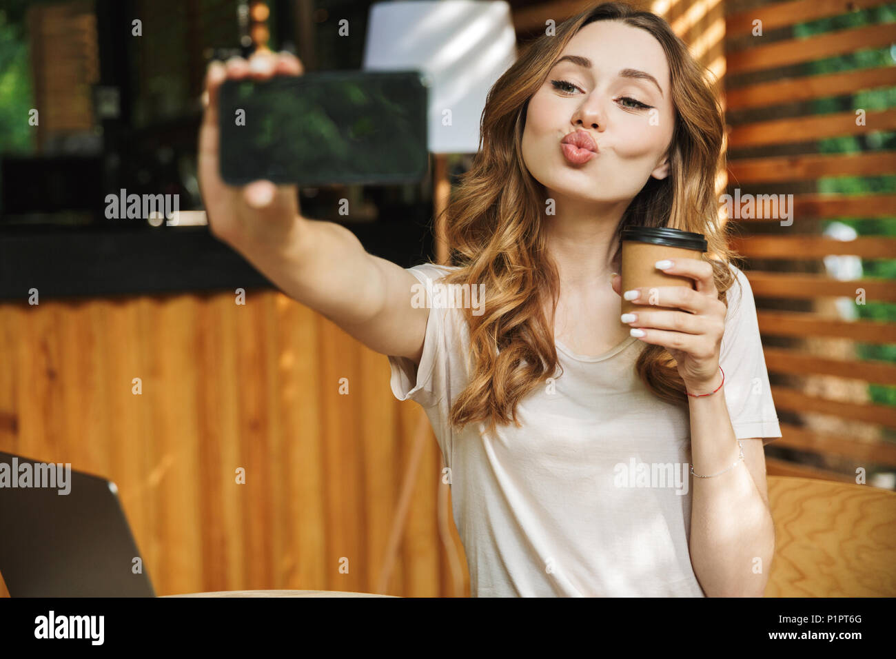 Portrait of a pretty young girl taking selfie with mobile phone while ...