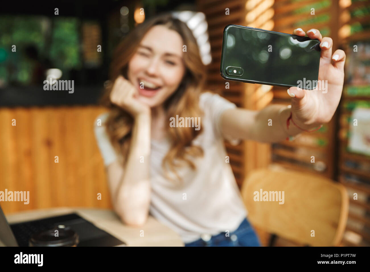 Portrait of a happy young girl taking selfie with mobile phone while ...