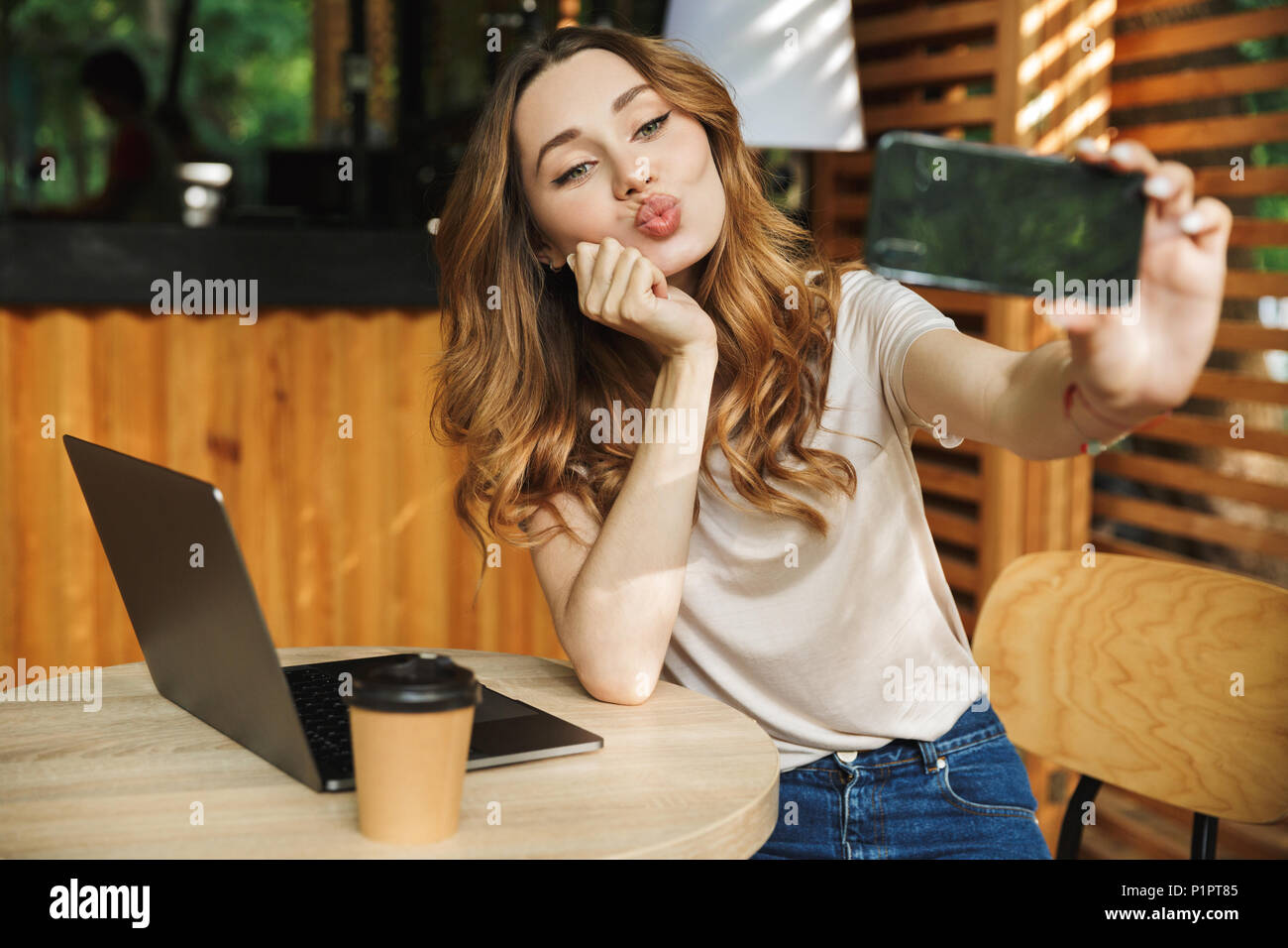 Portrait of a lovely young girl taking selfie with mobile phone while ...