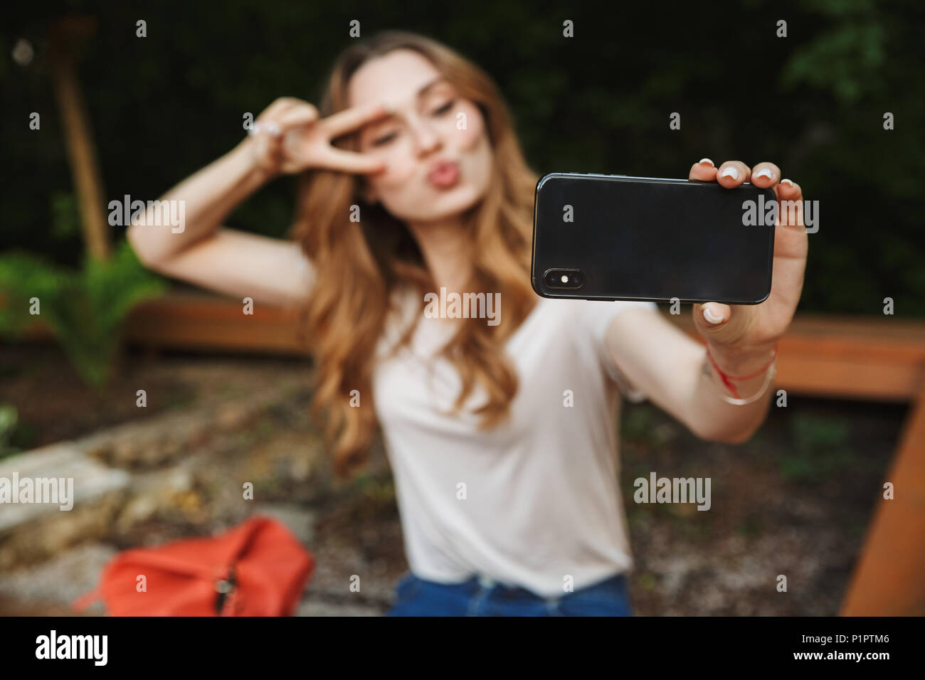 Pretty young girl taking selfie while sitting on a bench outdoors Stock ...