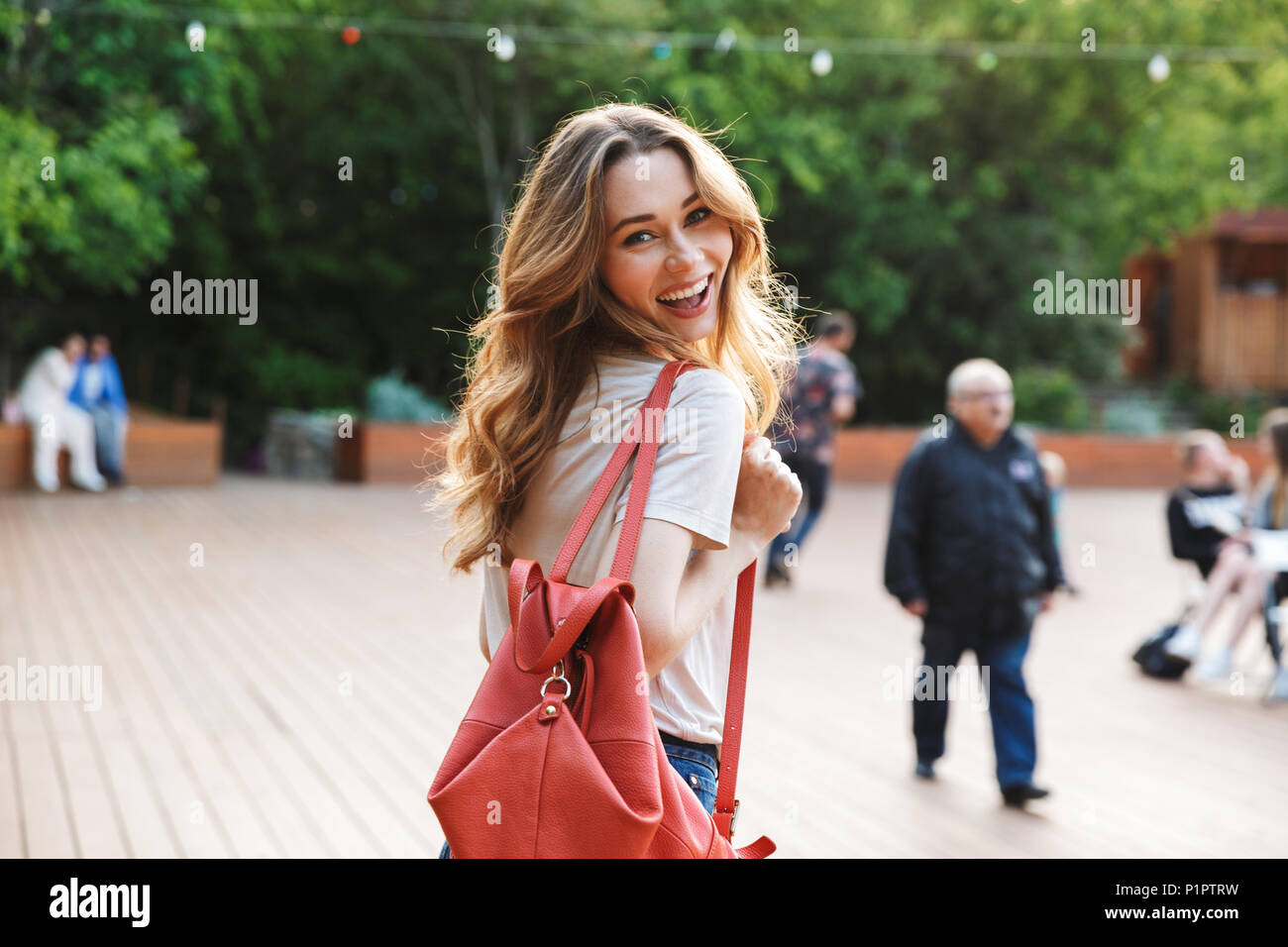 Smiling young woman with backpack walking outdoors Stock Photo - Alamy