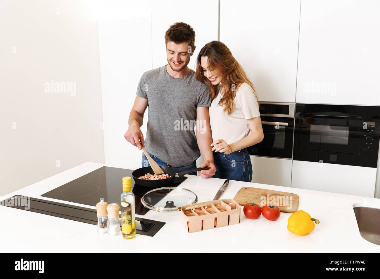 Pretty young couple cooking breakfast together Stock Photo - Alamy