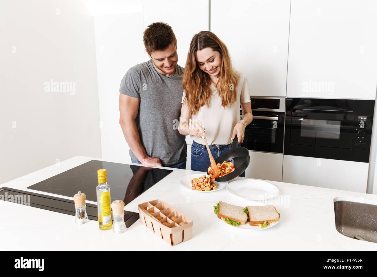Smiling young couple cooking breakfast together in a kitchen Stock ...