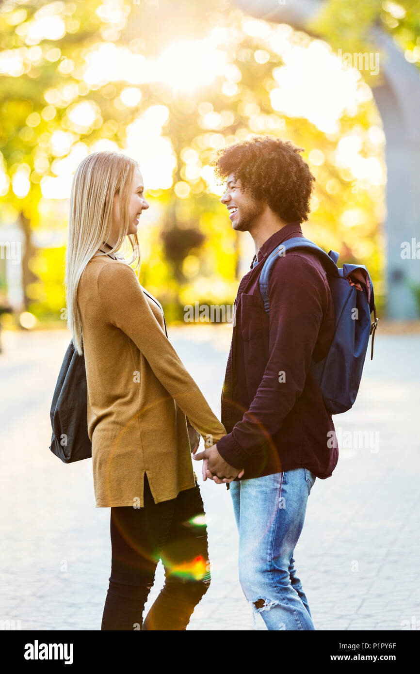 Boyfriend and girlfriend standing and looking at each other while ...