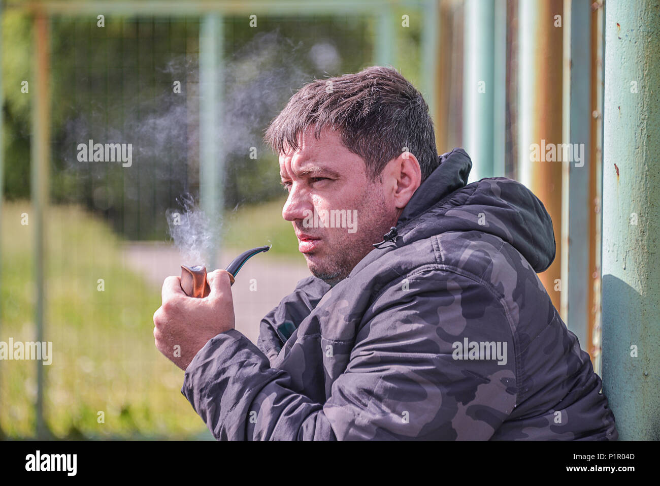the man is smoking a pipe, close-up, in the cool windy weather, the ...