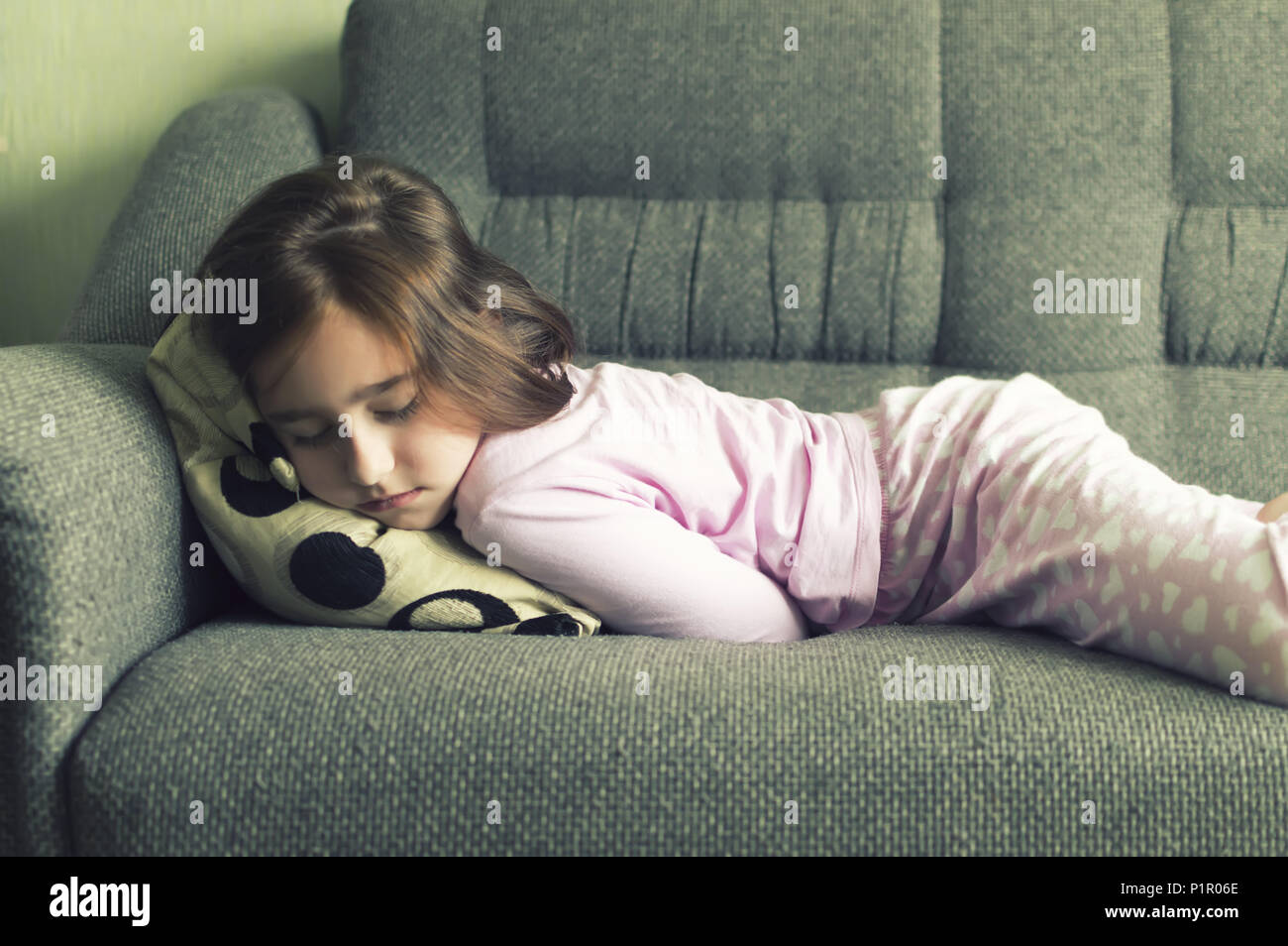 child in a night suit tired, sick, lay down on the couch, is depressed ...